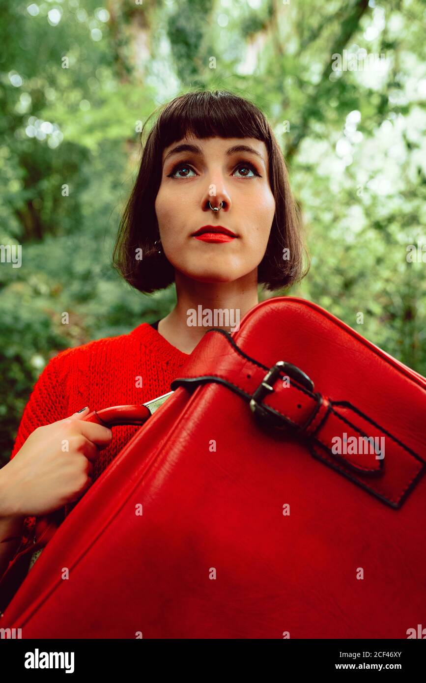 Woman in red with big red suitcase in forest Stock Photo - Alamy