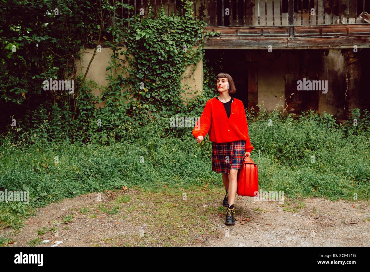 Woman in red with big red suitcase in forest Stock Photo - Alamy