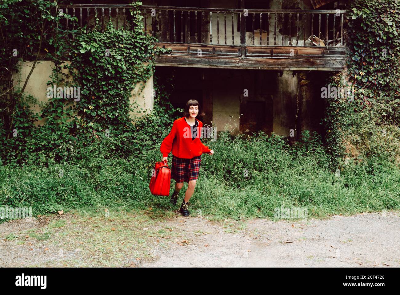 Woman in red with big red suitcase in forest Stock Photo - Alamy