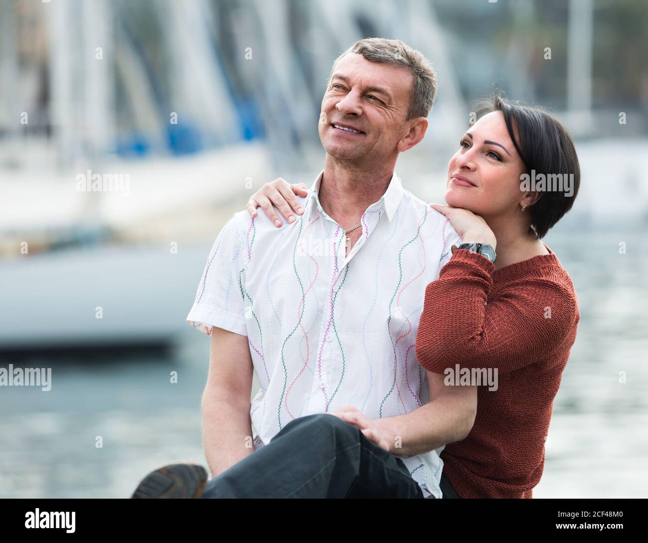 Portrait of loving mature couple hugging against water landscape Stock ...