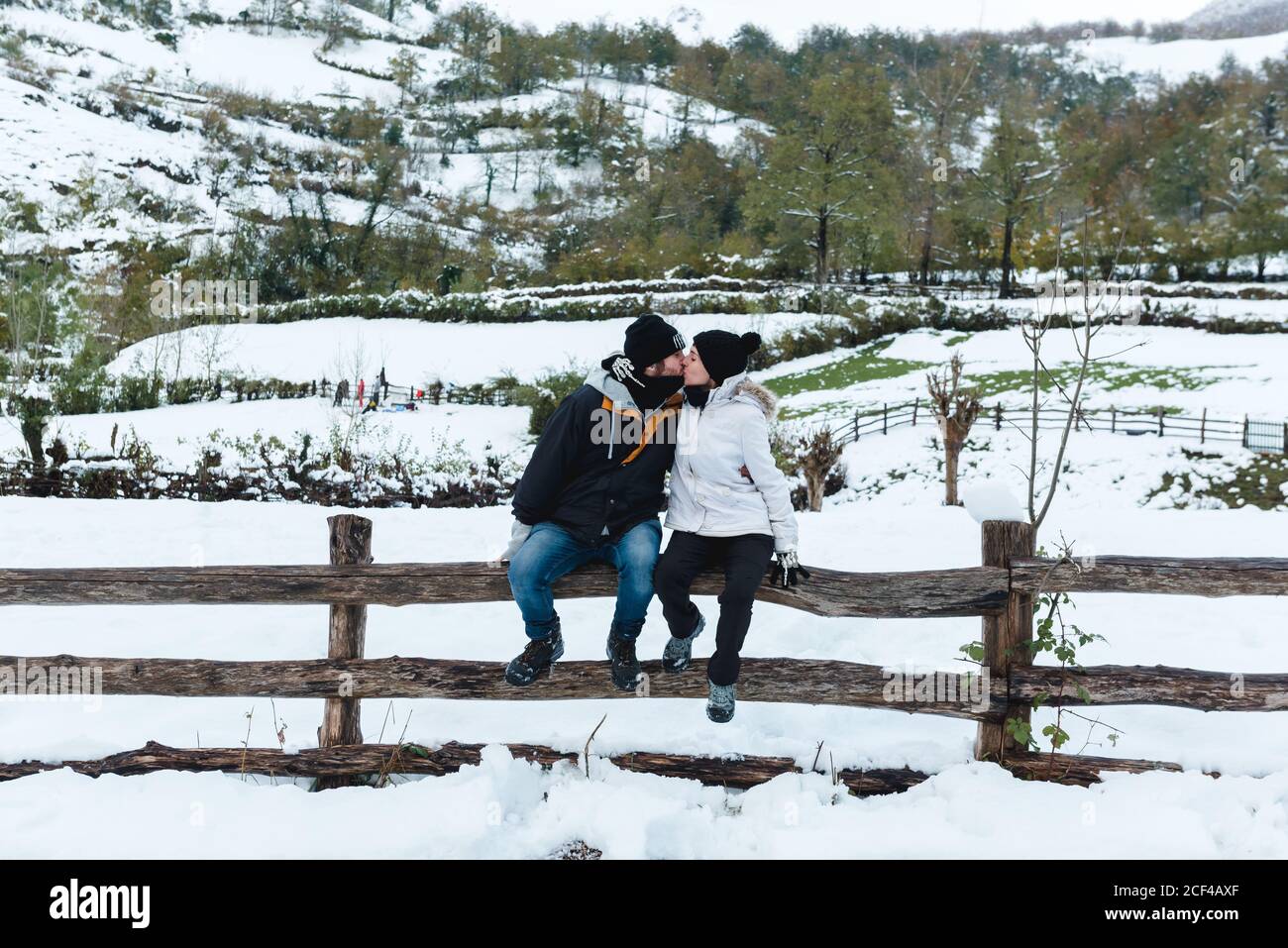 Romantic man and Woman wearing winter clothes kissing while sitting on ...