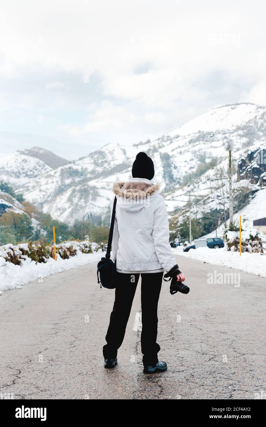 Back view of faceless person in white winter jacket with hood on head ...
