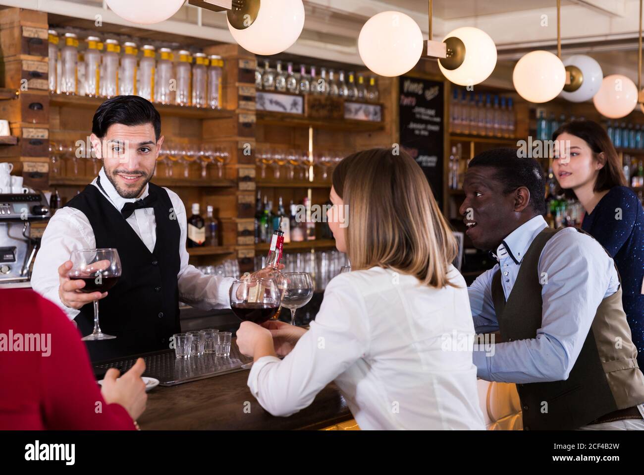 Young people are relaxing near bar counter and drinking alcohol in ...