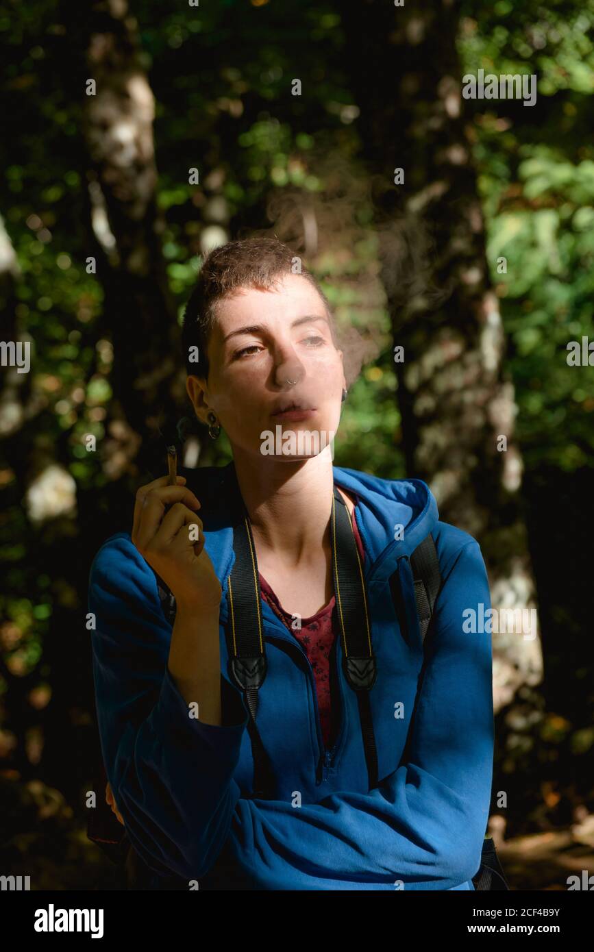 Calm young female tourist resting and smoking marijuana joint while ...