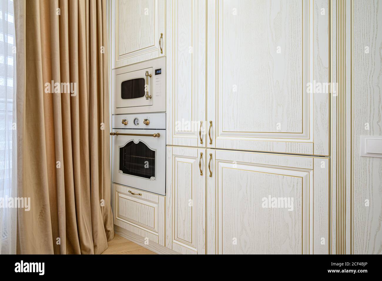 Electric and microwave ovens at beige kitchen interior Stock Photo - Alamy