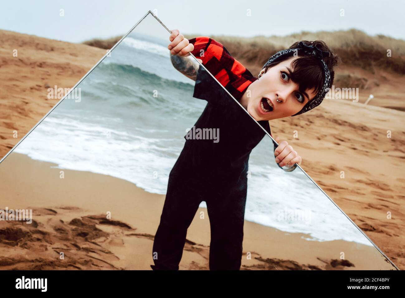 Woman on beach holding mirror with male reflection Stock Photo - Alamy