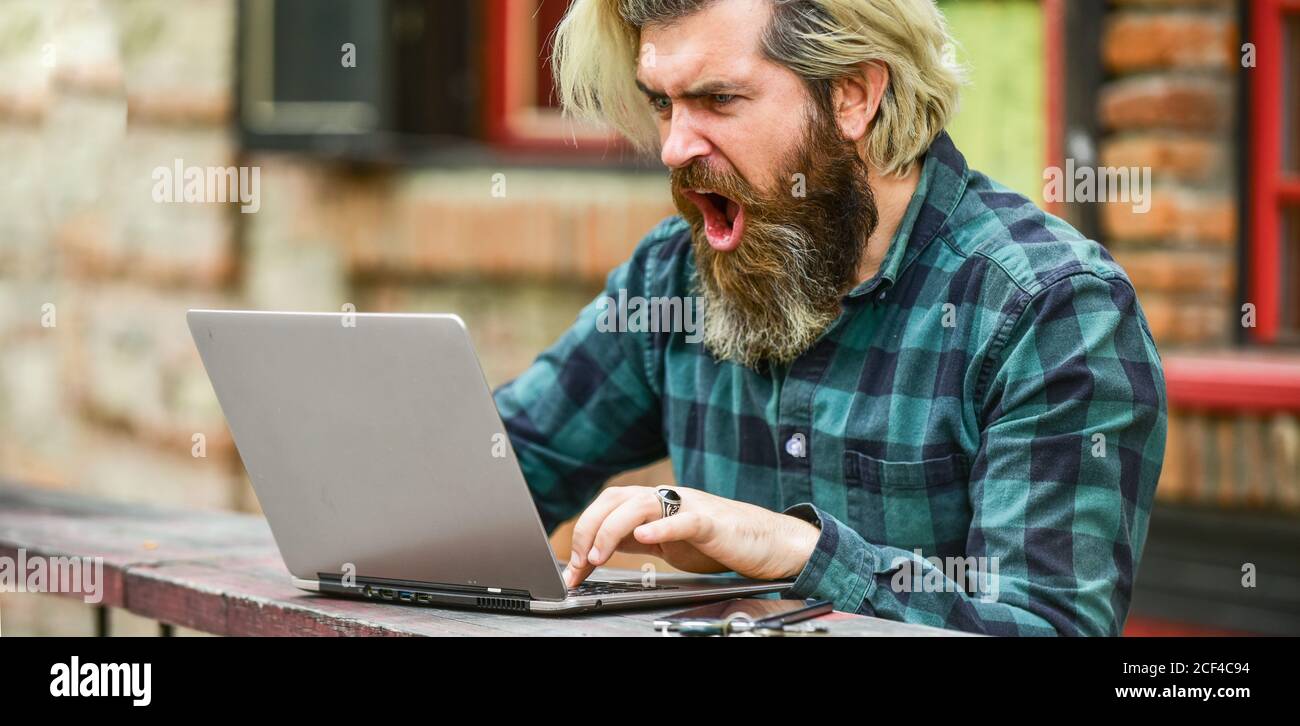 Living in digital age. angry man sitting in cafe with laptop and ...