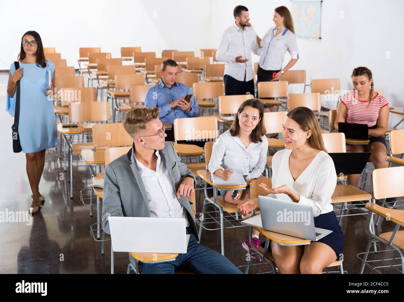 Happy group of adult students lively chatting while enjoying free time ...