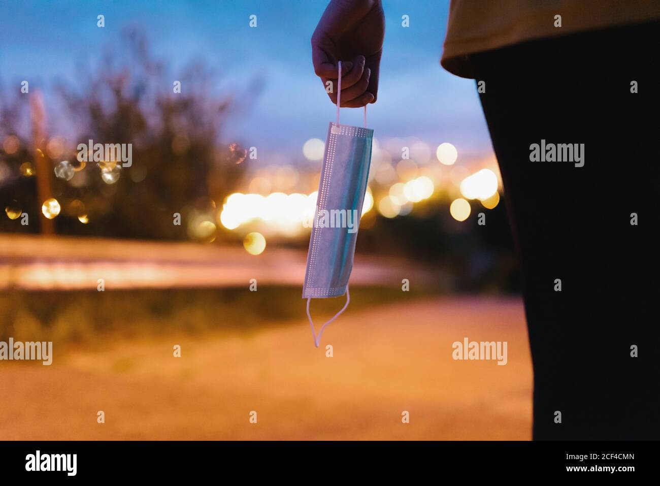 anonymous person in casual clothes standing on street in evening and ...