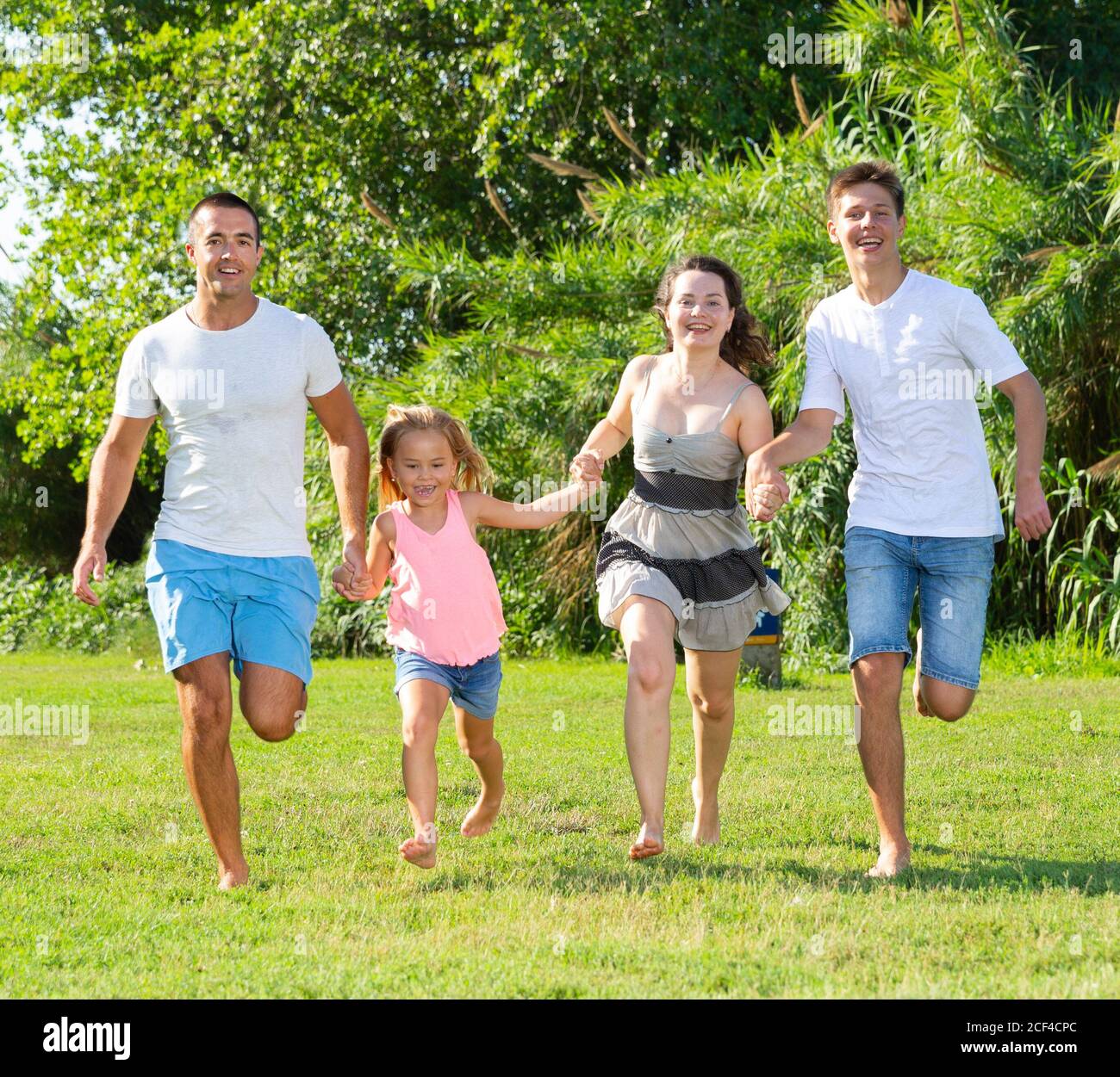 Cheerful family with two children having fun together, running in ...