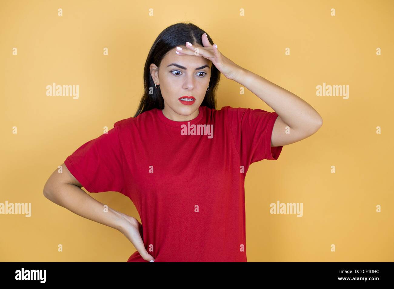 Young beautiful woman over isolated yellow background with a worried ...
