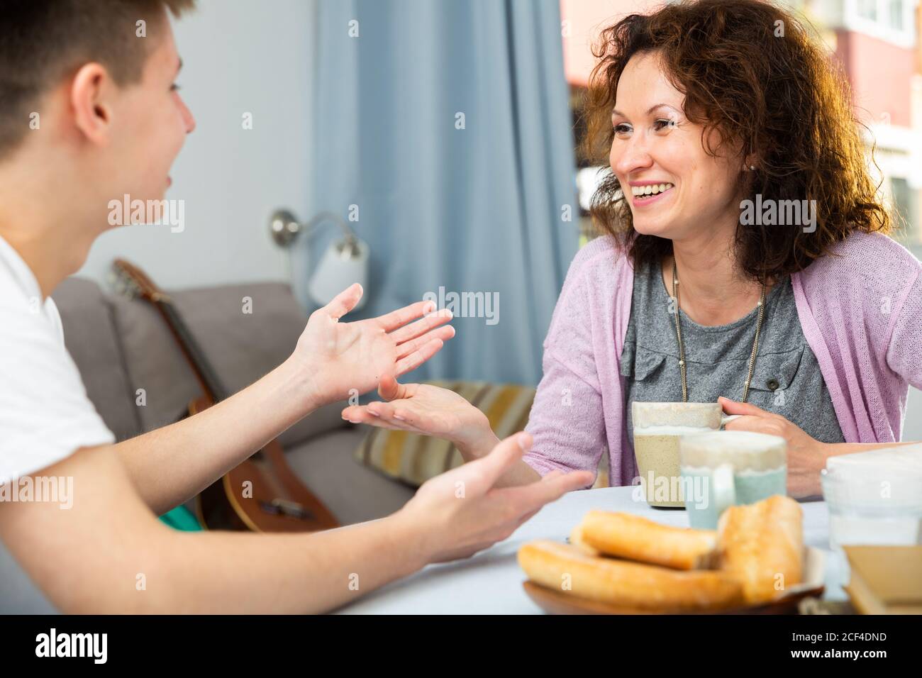 Happy family of mother and teenage son enjoying conversation at home ...