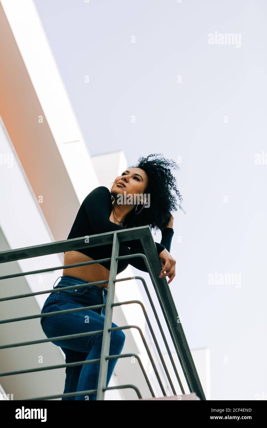 From below young beautiful woman flying curly hair standing balcony hi ...