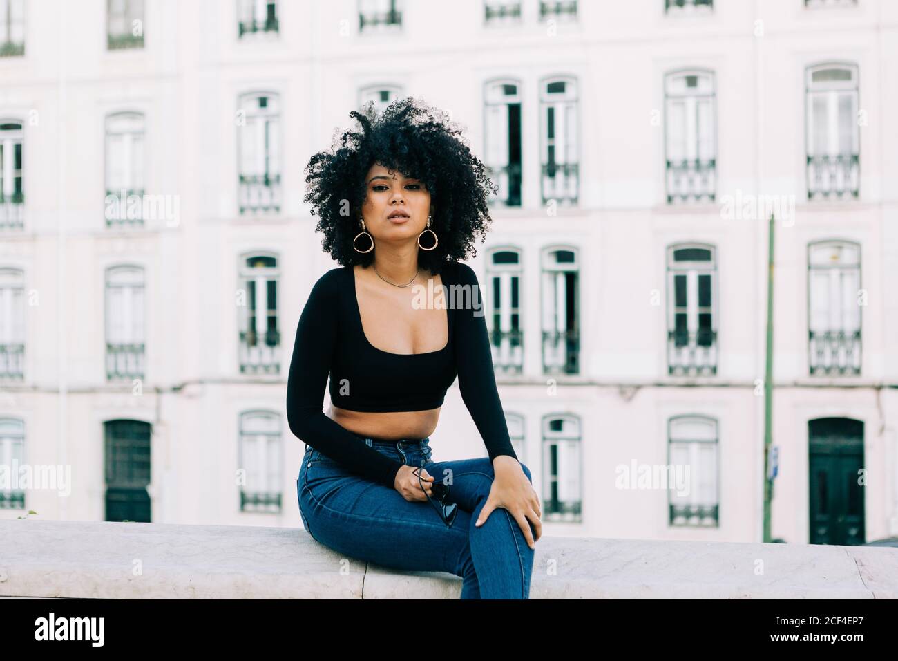 Young trendy African American Woman in jeans and crop top sitting on ...