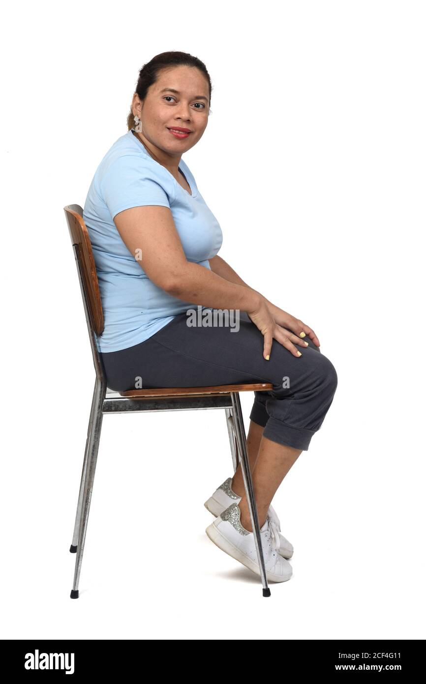 side view of a woman sitting on a chair looking at camera on white ...