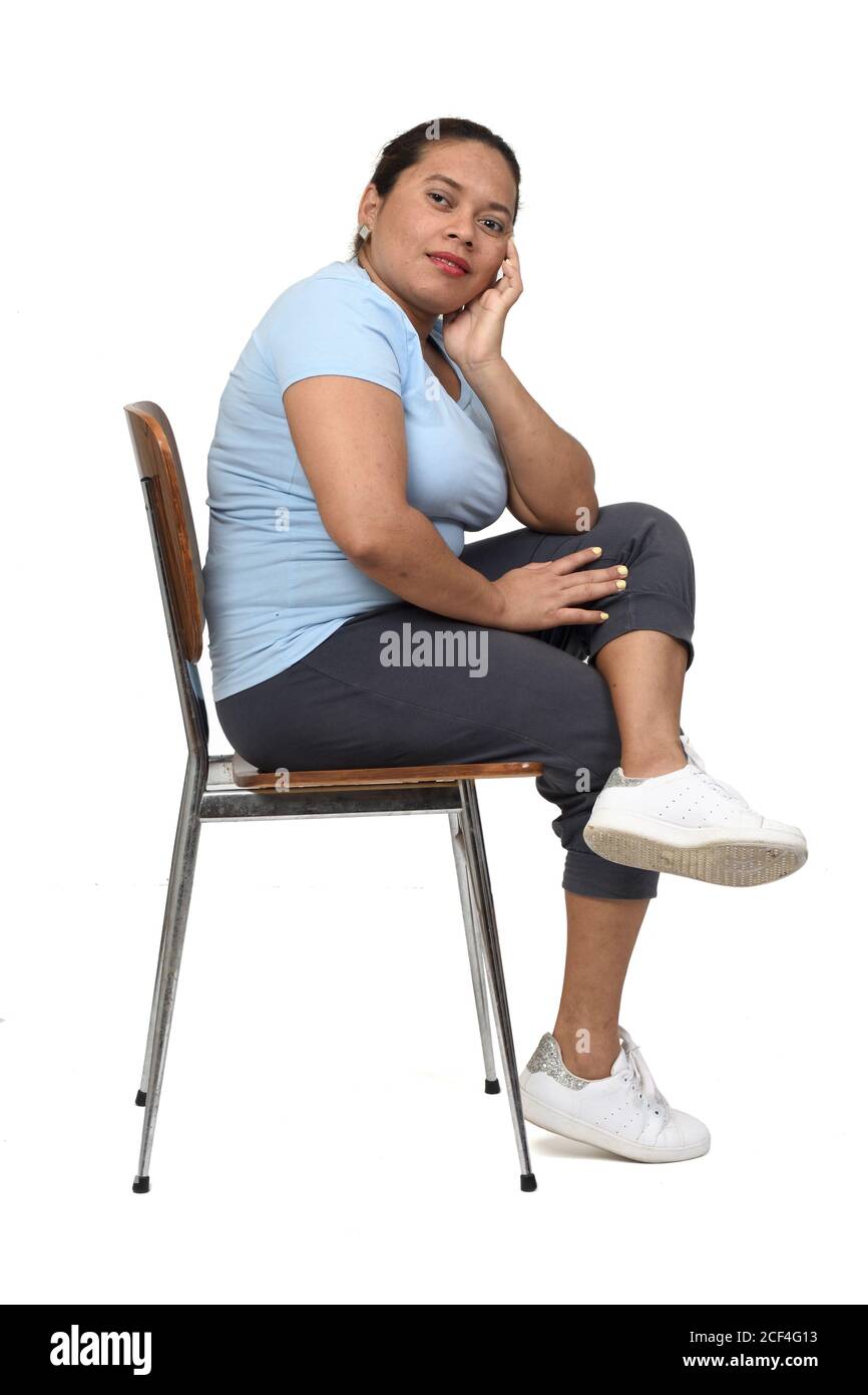 side view of a woman sitting on a chair looking at camera on white ...