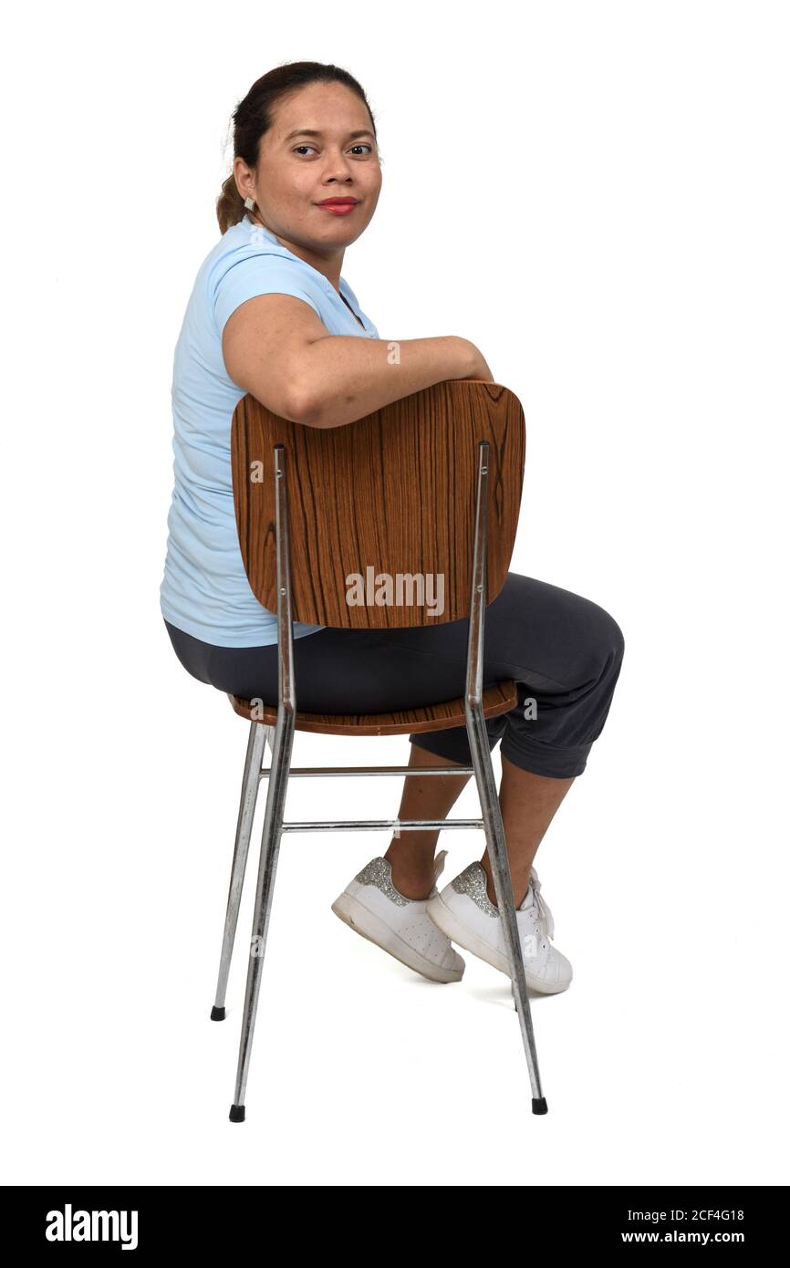 side view of a woman sitting on a chair looking at camera on white ...