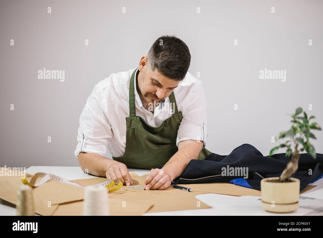 Male seamstress using measuring tape while checking exact size of ...
