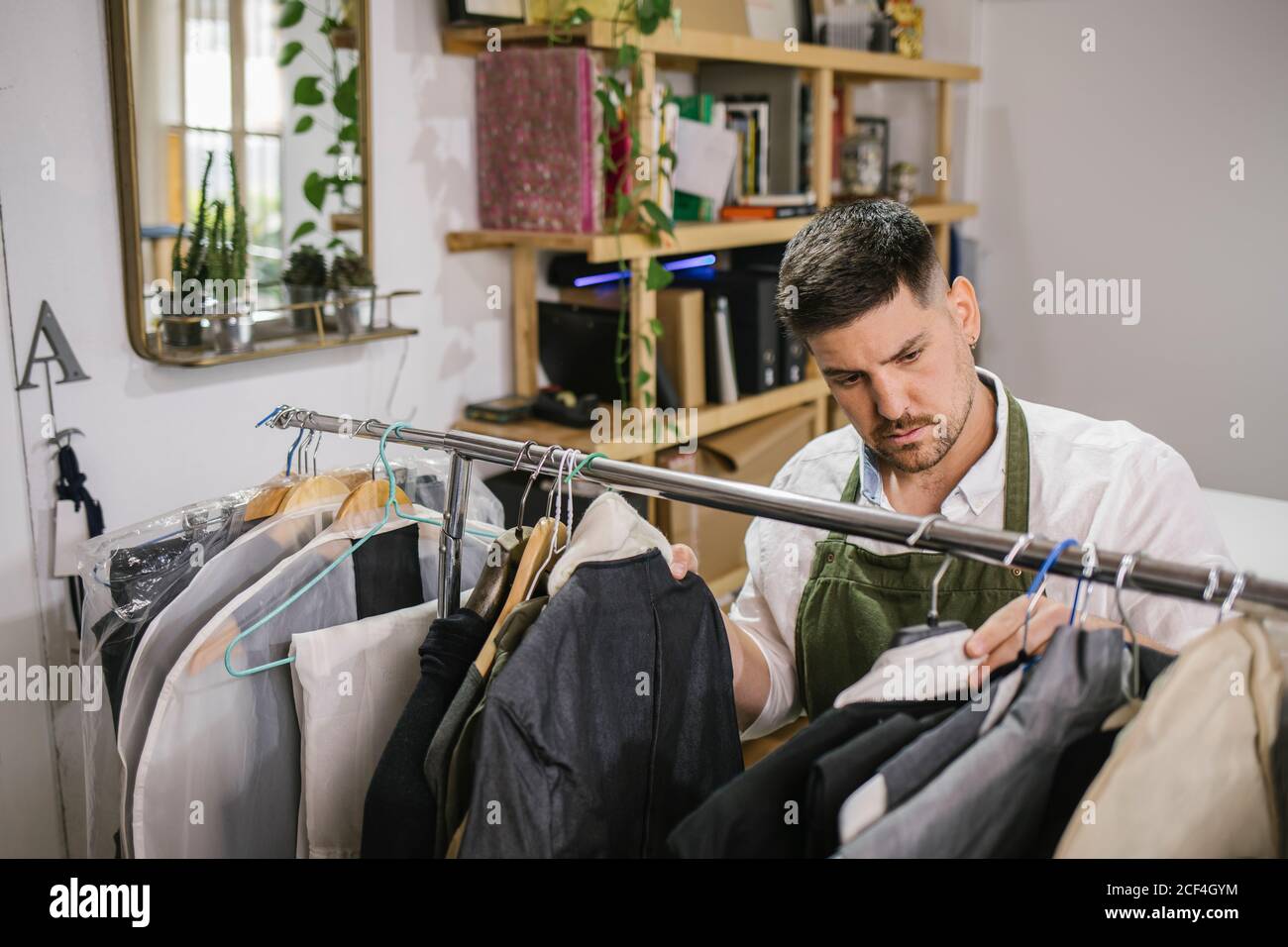 High angle of serious focused male tailor in apron checking details of ...