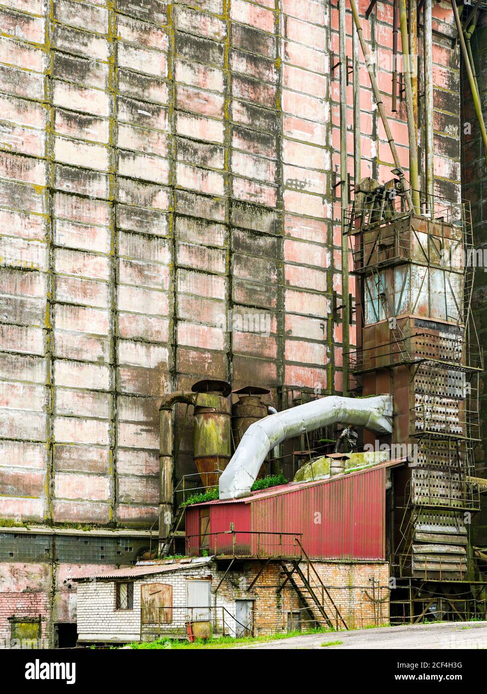 old factory building wall with auxiliary buildings and various pipes ...
