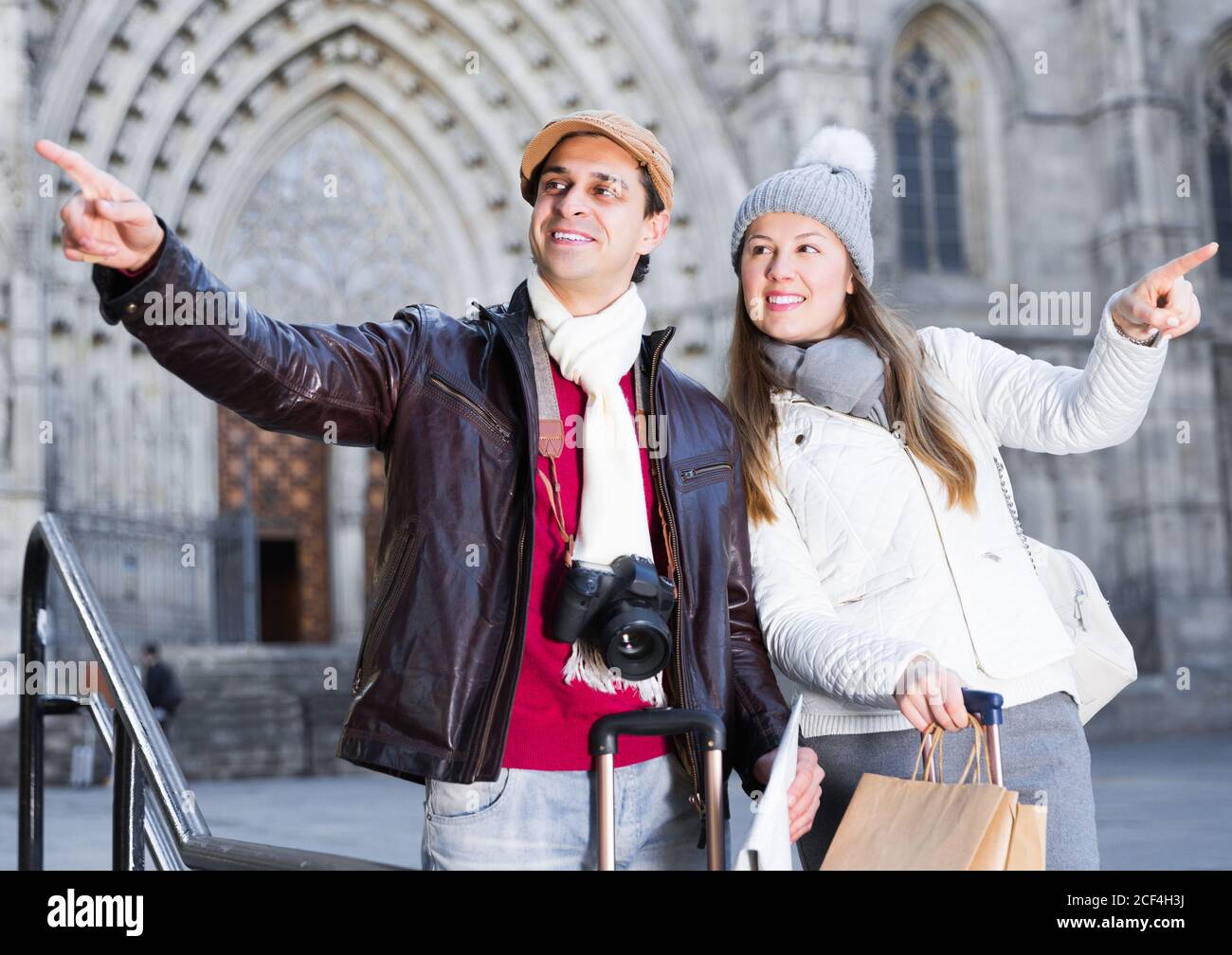 smiling active young male and female in the historic center pointing ...