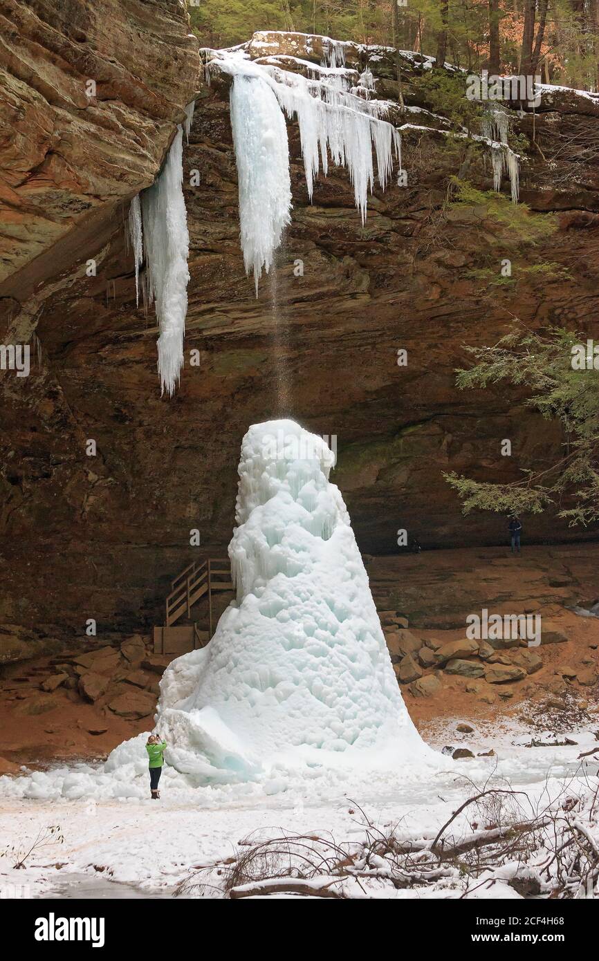 Woman photographs giant ice cone that has formed at the base of the ...