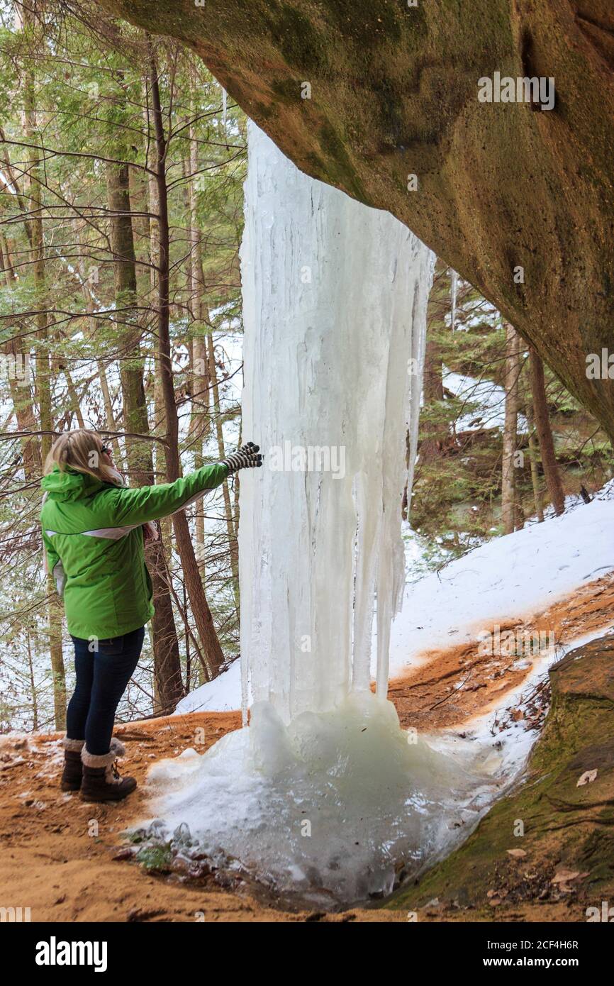 Woman inspects frozen column of ice at Saltpetre Cave, part of the ...