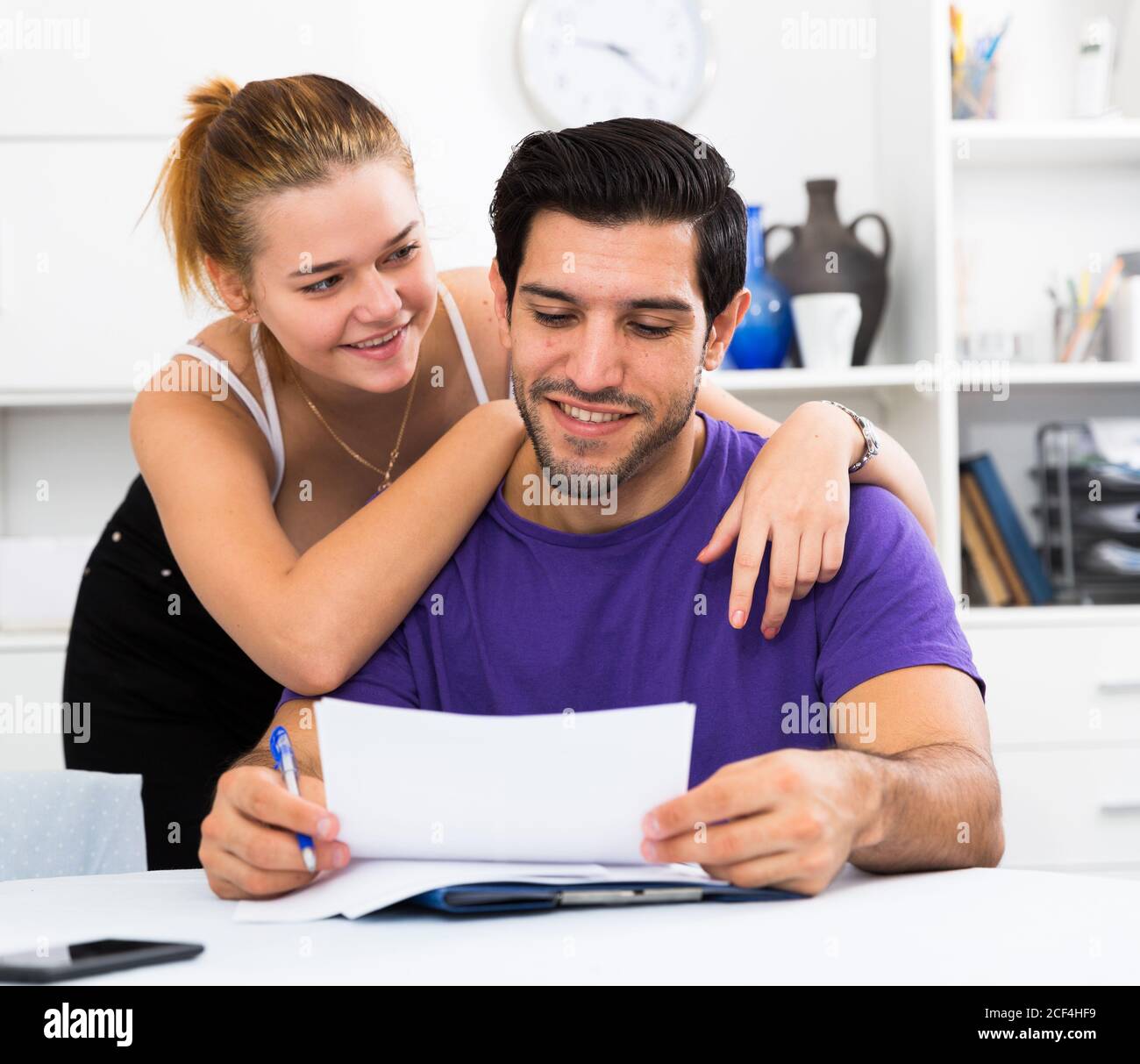 Happy young man and woman reading mail together and checking ...