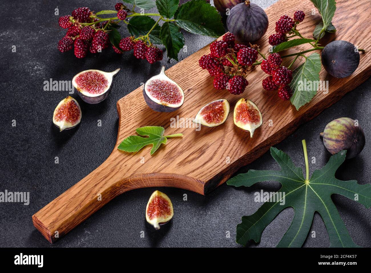 Fresh juicy figs and blackberries on a dark background. Harvesting ...