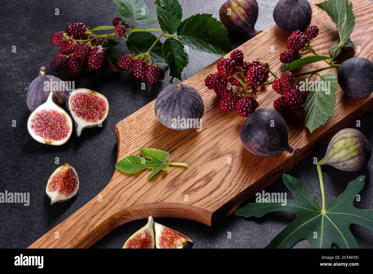 Fresh juicy figs and blackberries on a dark background. Harvesting ...