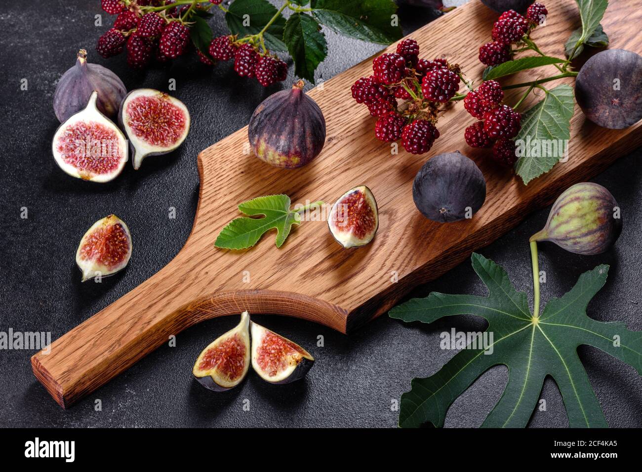 Fresh juicy figs and blackberries on a dark background. Harvesting ...