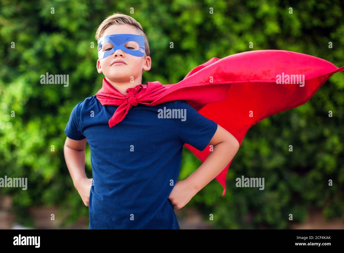 Superhero kid boy against green background outdoor. Childhood, success ...
