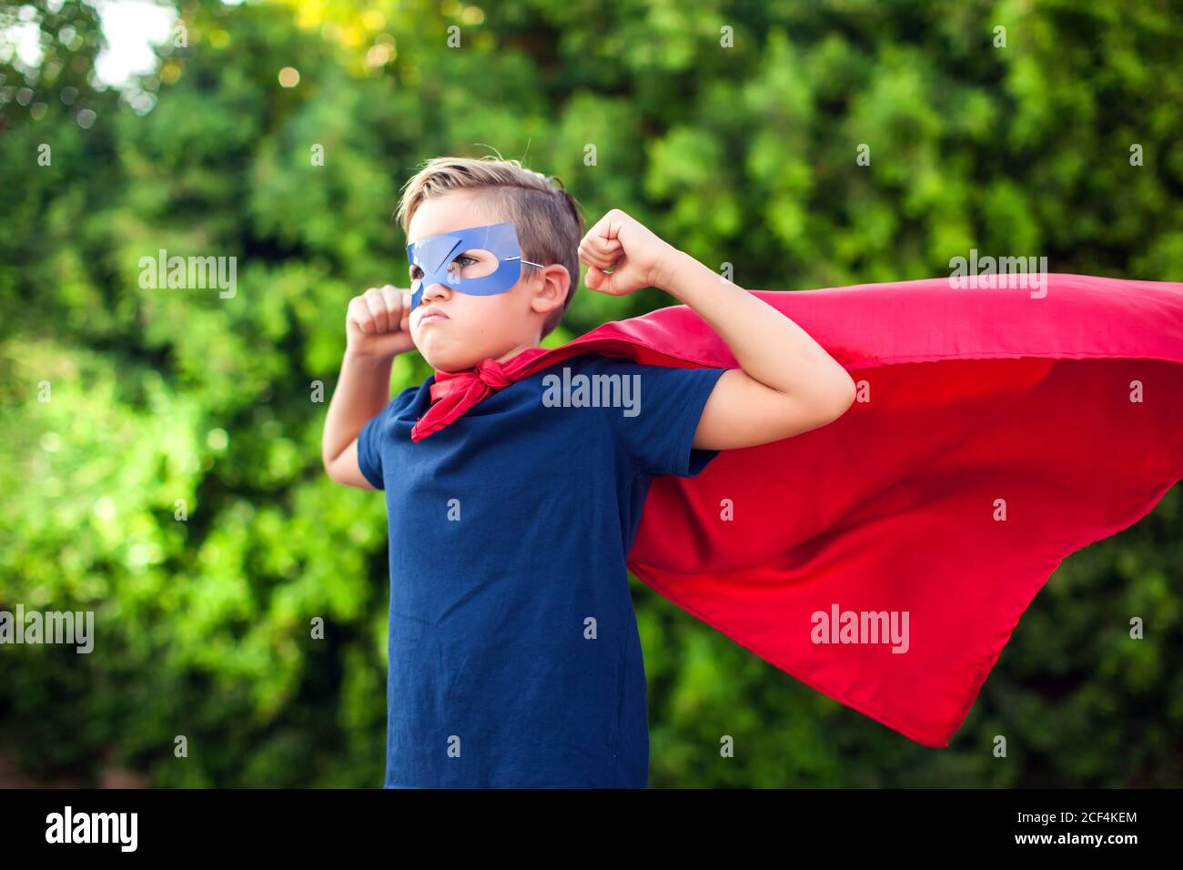 Superhero kid boy against green background outdoor. Childhood, success ...