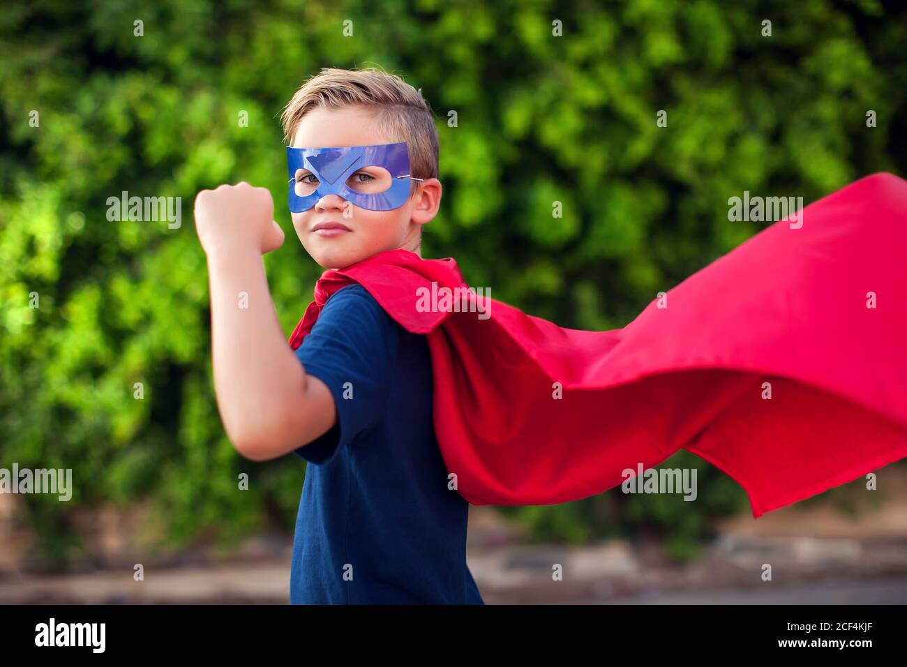 Superhero kid boy against green background outdoor. Childhood, success ...
