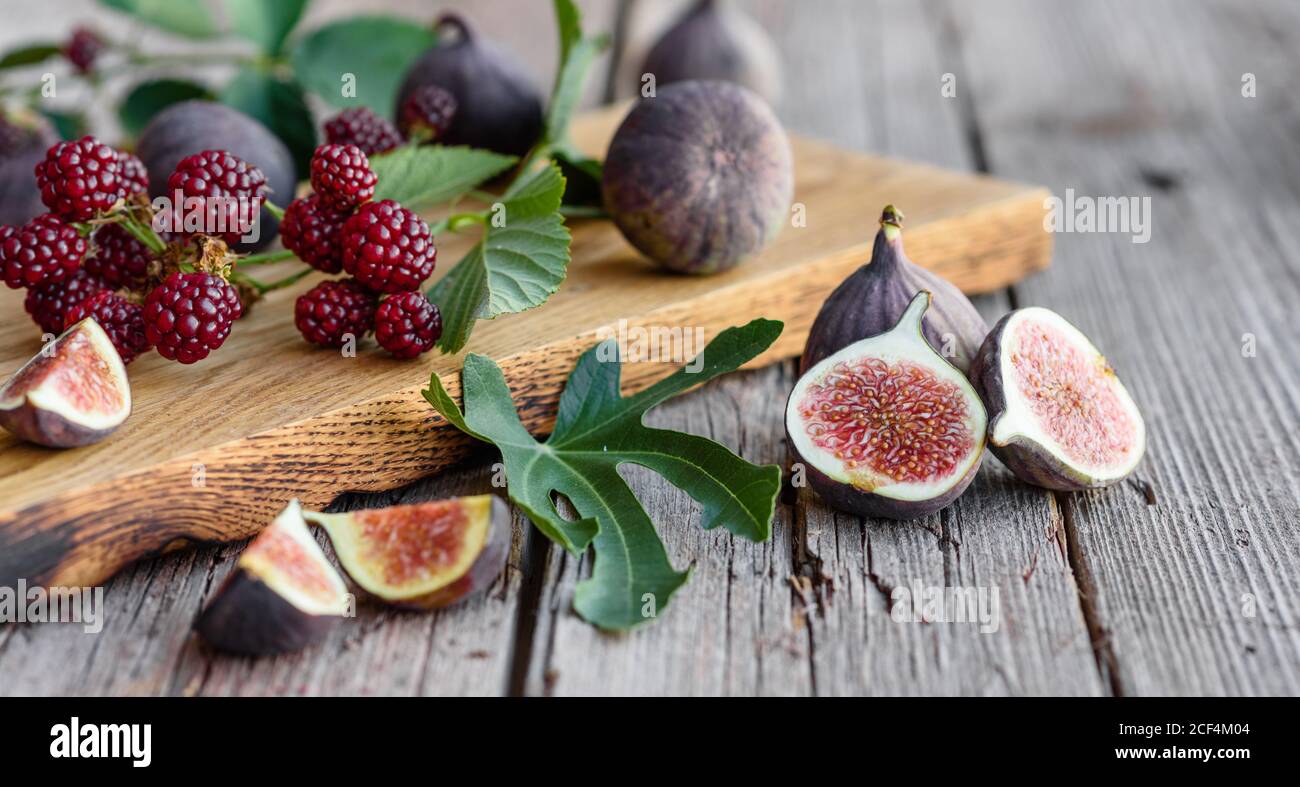 Fresh juicy figs and blackberries on a dark background. Harvesting ...