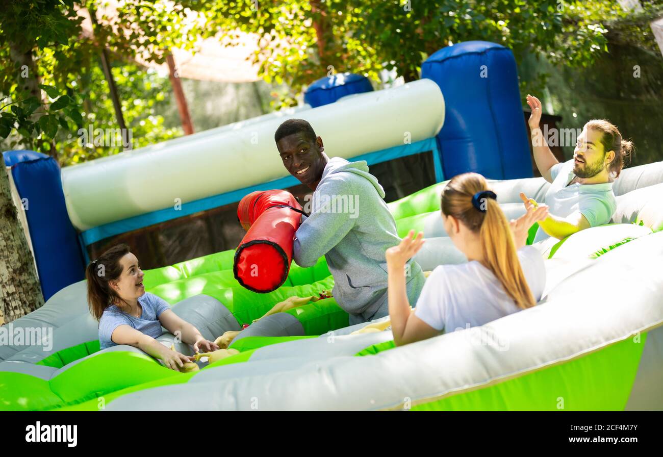 Funny friends playing on an inflatable trampoline in an amusement park ...