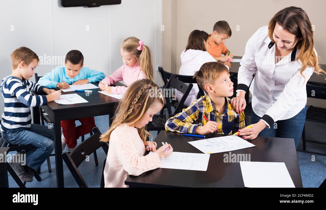 Positive little boys and girls with teacher drawing in classroom Stock ...