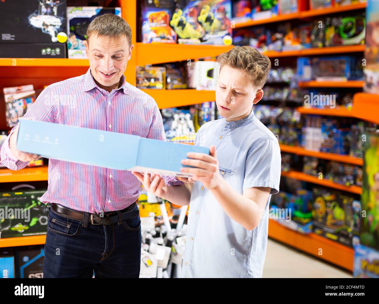 Teen boy with father visiting children toy store in search of new toys ...