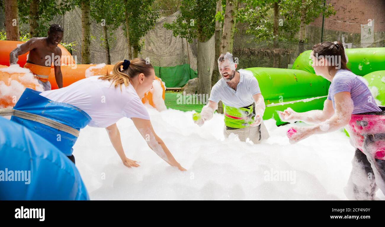 Cheerful friends having fun in outdoor amusement park, picking up balls ...