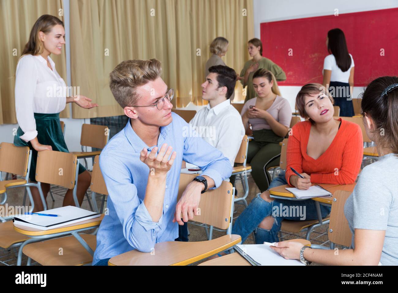 Friendly student group talking in classroom having break between ...