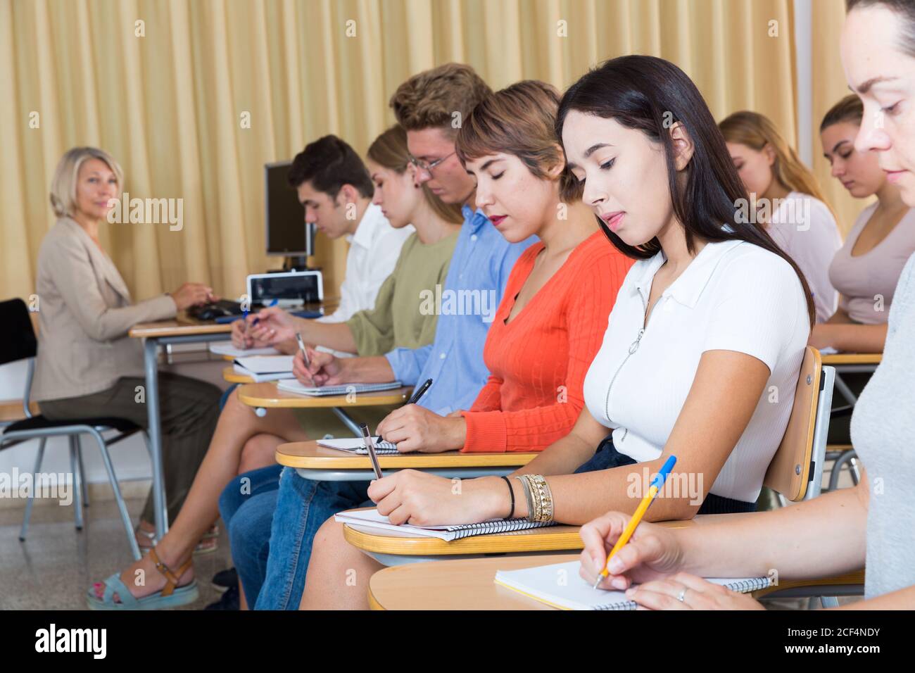 Side view of student group working with female teacher on lecture in ...