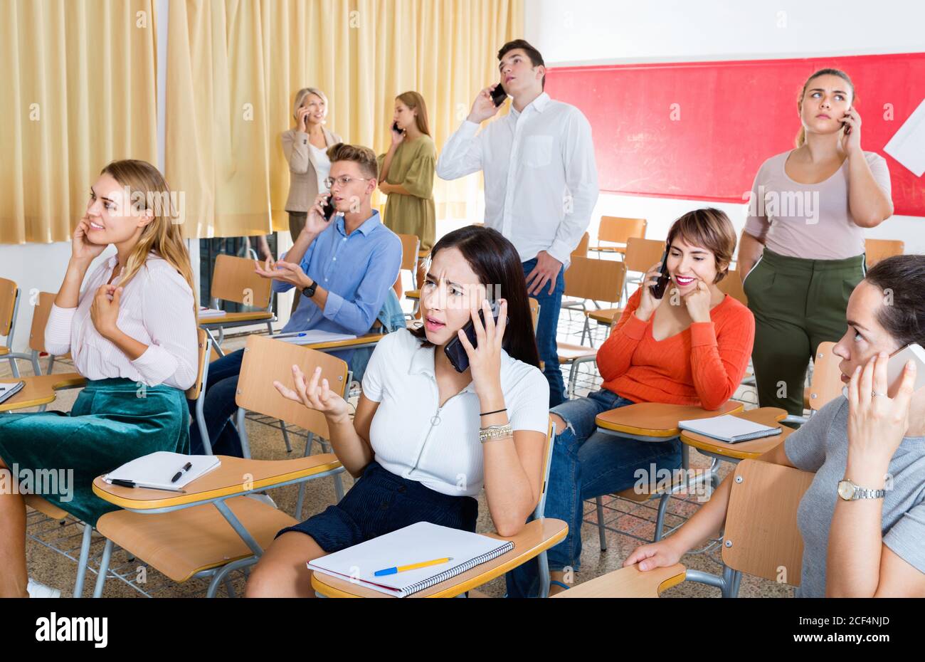 Group of positive glad students talking on phones during recess between ...