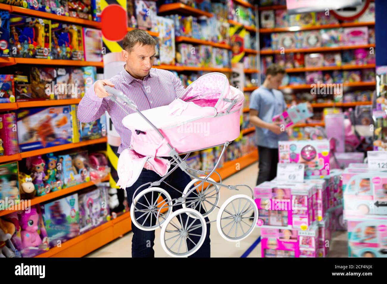 Caring glad cheerful positive smiling father choosing pink baby doll ...