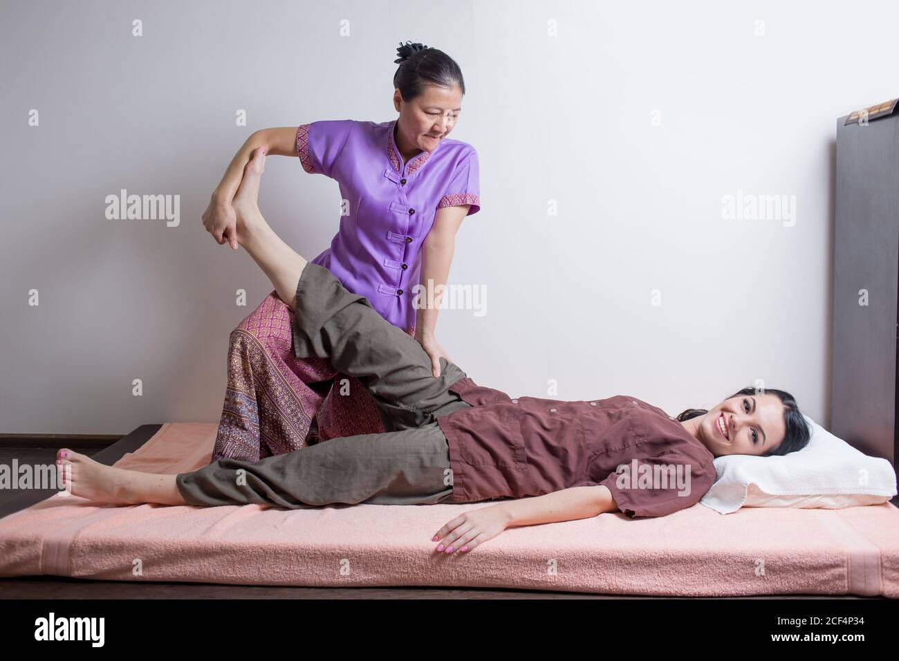 Therapist giving Thai stretching massage to woman Stock Photo - Alamy