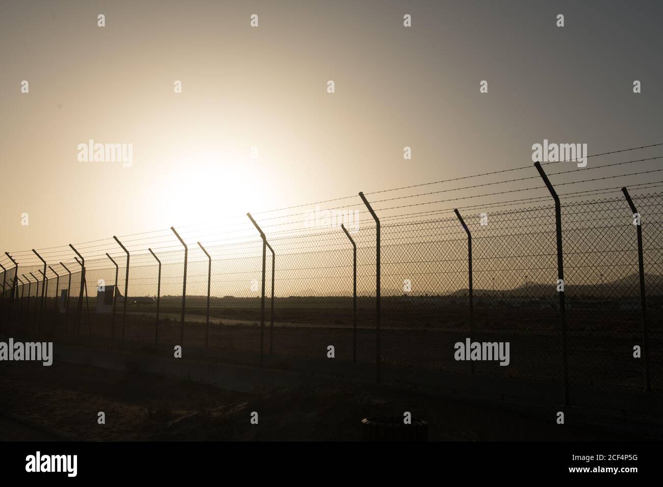 Bright sun behind security fence Stock Photo - Alamy