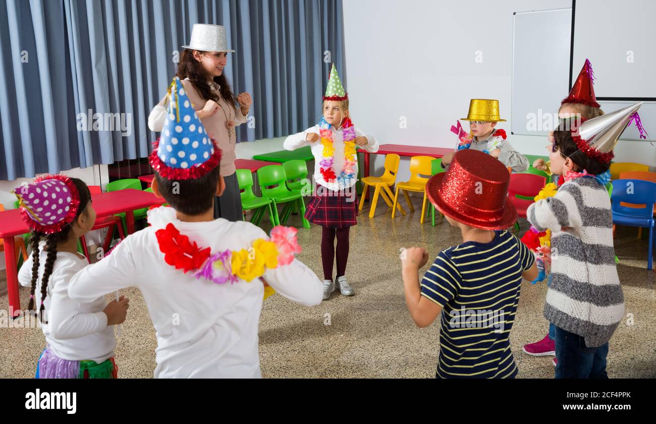 Group of cheerful school kids wearing festive hats having fun with ...