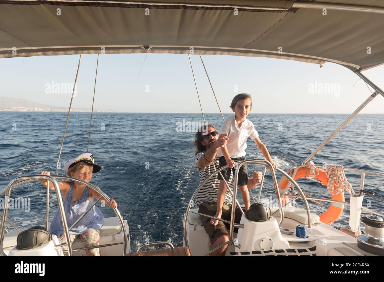 Happy father with children floating on expensive boat on sea and blue ...