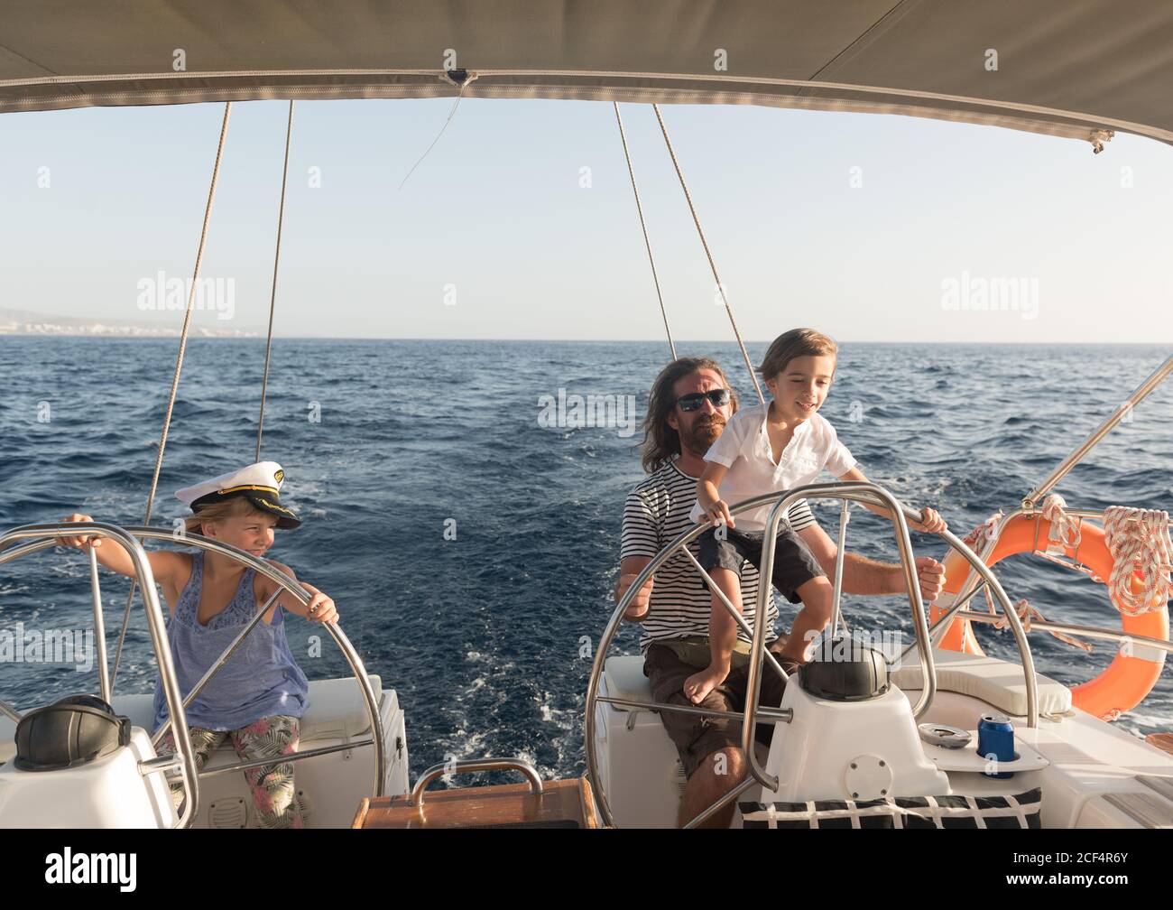 Happy father with children floating on expensive boat on sea and blue ...