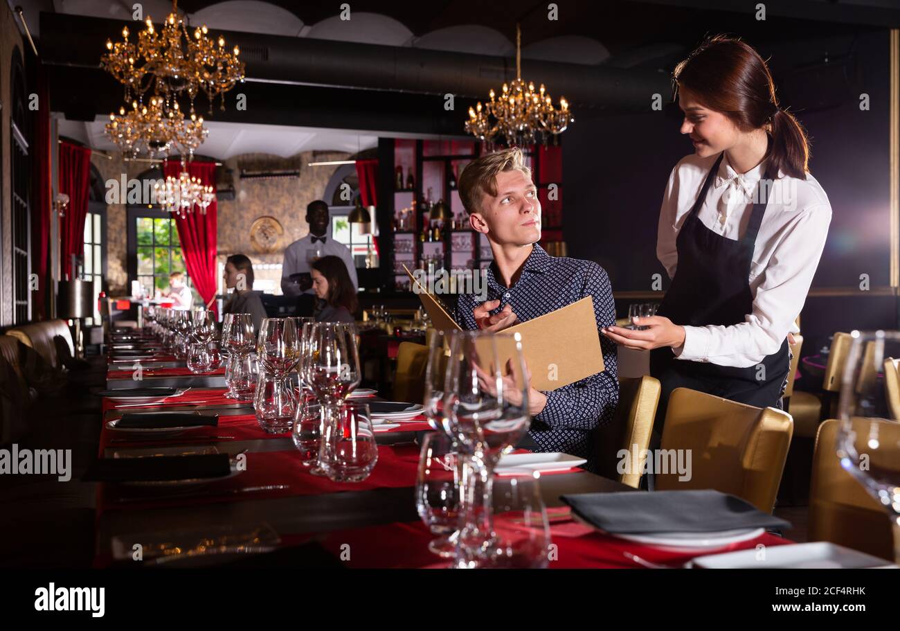Portrait of handsome young man holding menu and ordering food in luxury ...