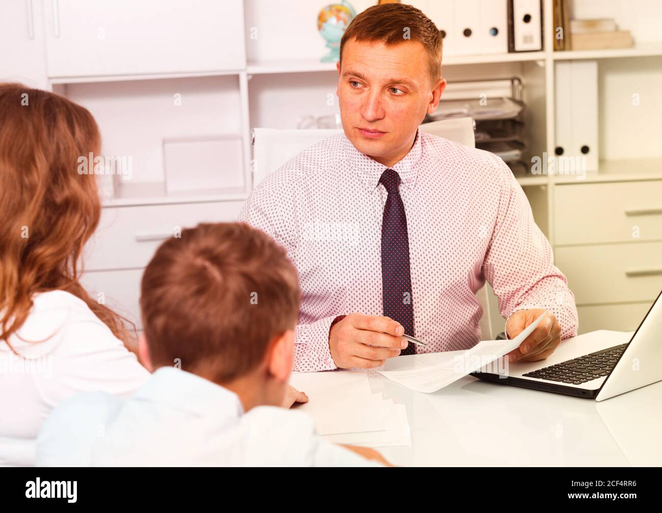 Middle-aged mother and son visiting consultation with school headmaster ...